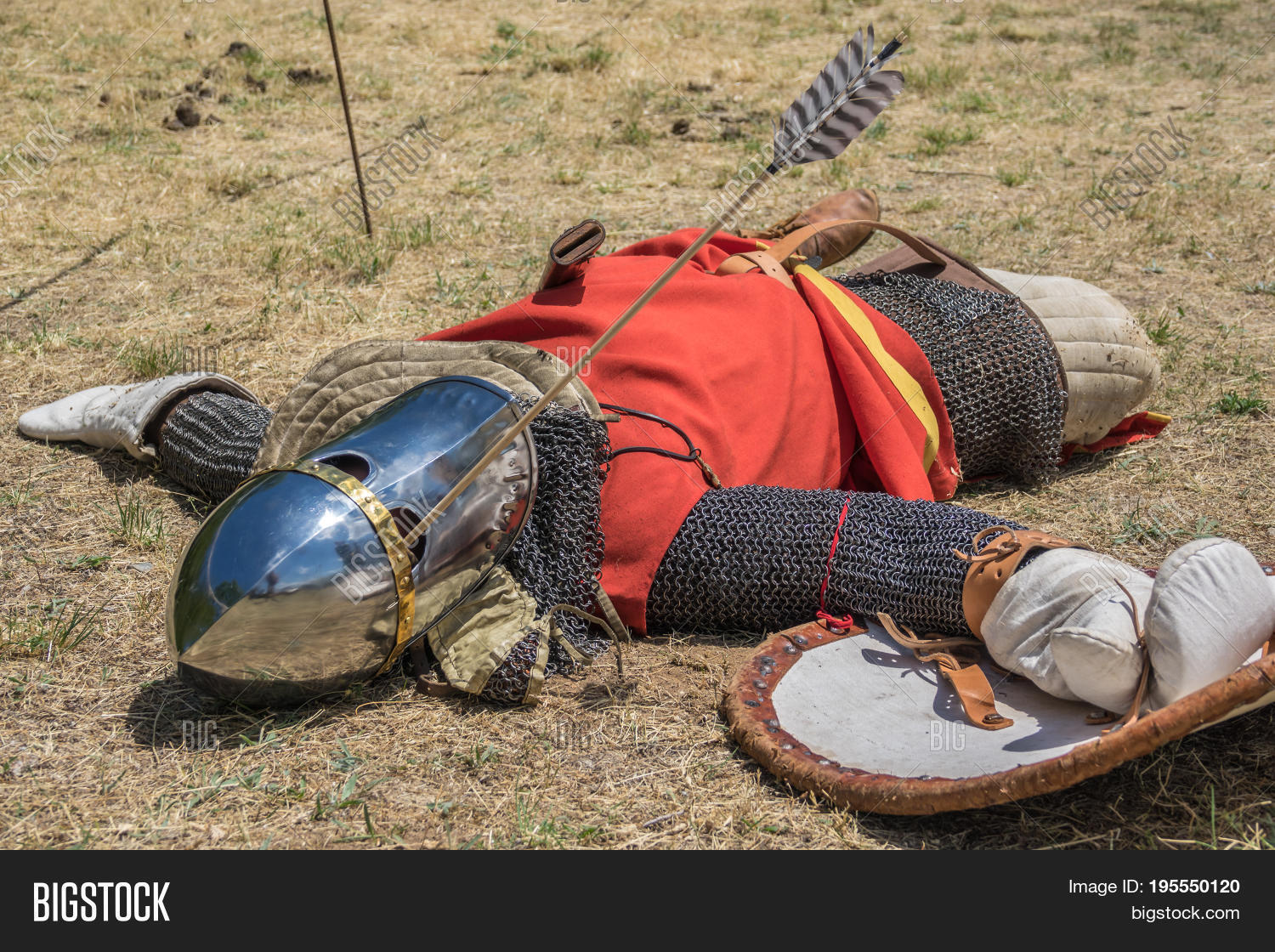 Medieval knight fallen in battle, with an arrow piercing his helmet and striking his head ...