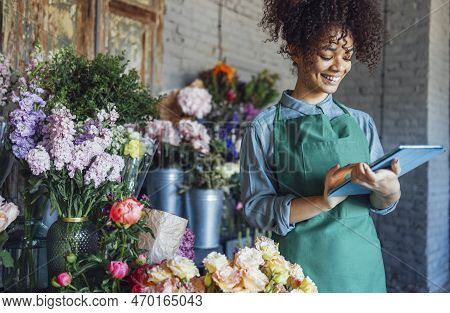 Young Black Woman Wearing Beige Apron On Flower Shop Background With ...