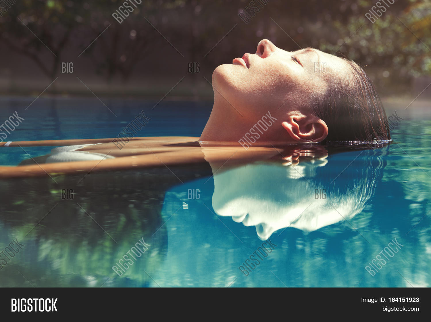Enjoy the summer. Woman relaxing in the pool water. A beautiful woman ...